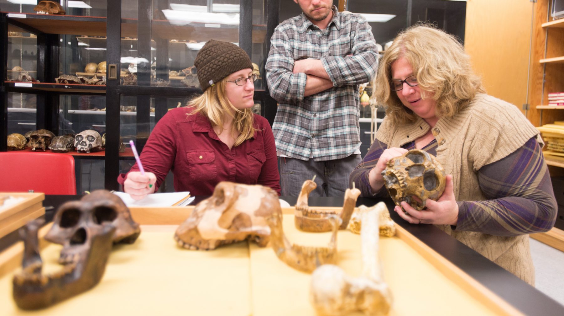Professor holding a skull in the bone lab with students - Anthropology ...